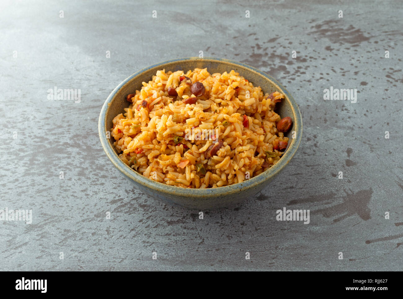 Side view of a bowl of Mexican rice and beans on a gray background ...