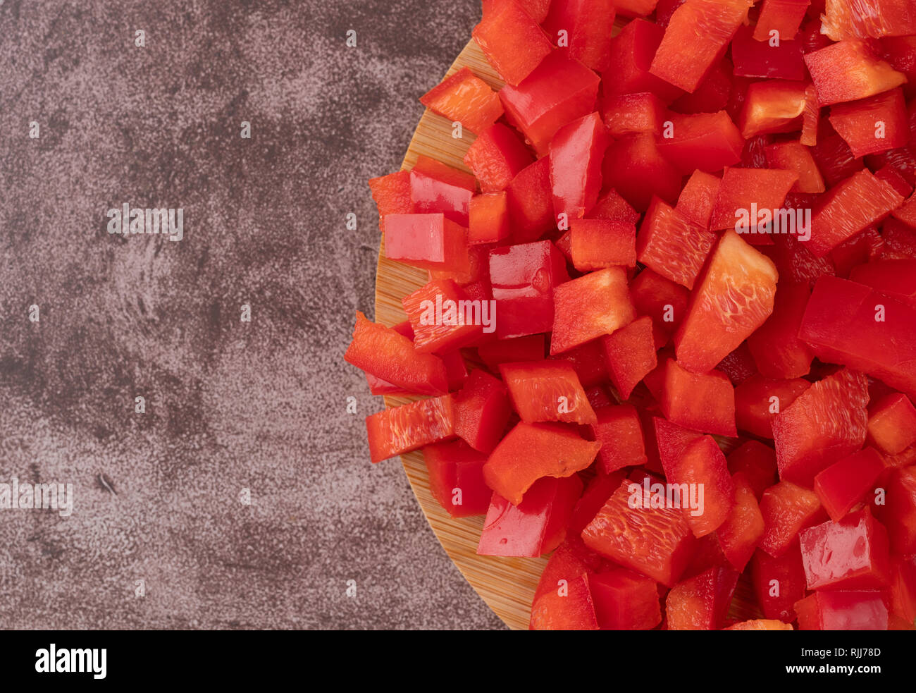 Top view of chopped red bell peppers on a wood cutting board atop a ...