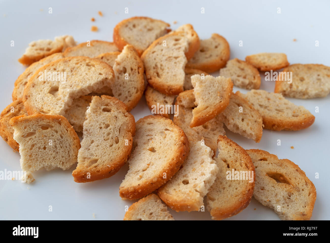 Side view of broken pieces of sesame round melba toast on a white plate ...