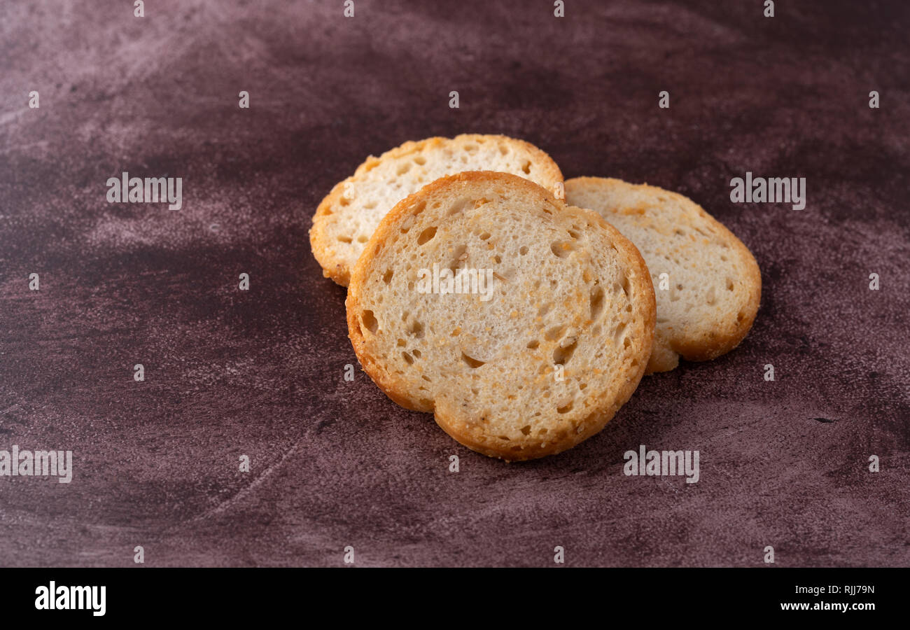 Side view of three slices of sesame round melba toast on a maroon ...
