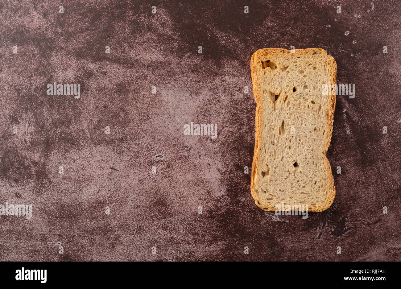 Top view of a slice of rye melba toast to the side on a maroon ...