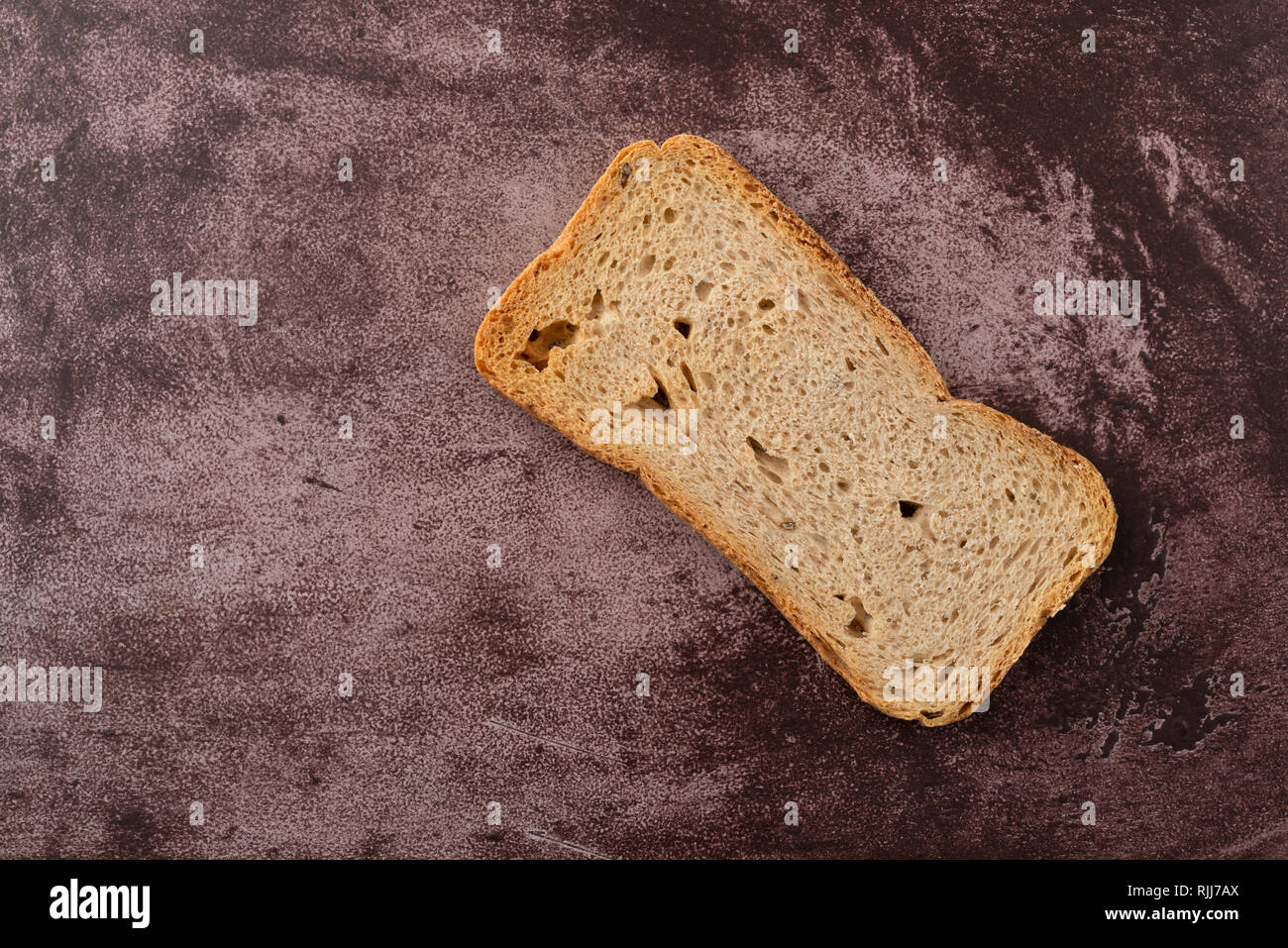 Top view of a slice of rye melba toast on a maroon background ...