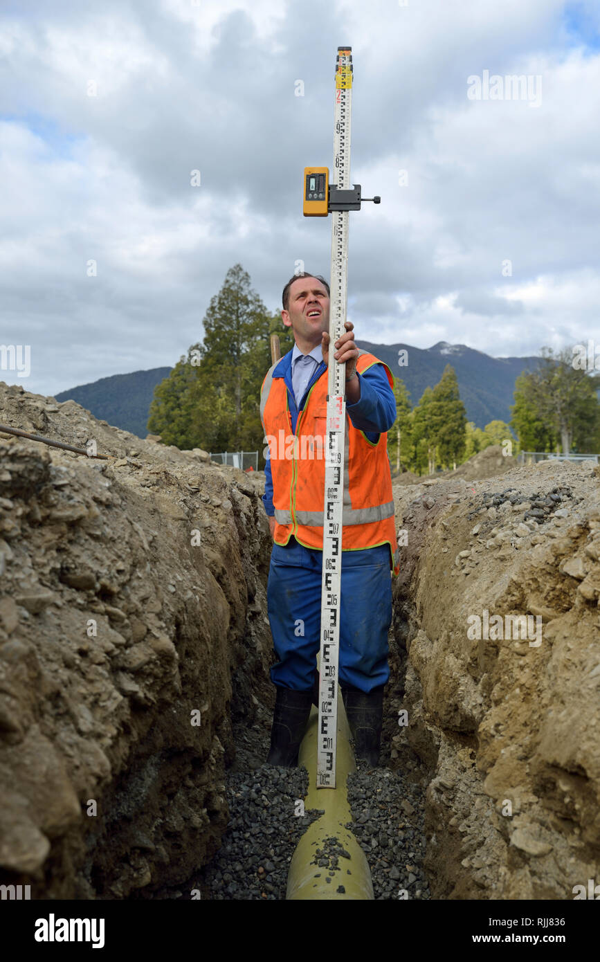 A tradesman checks the depth of a new stormwater drain Stock Photo - Alamy