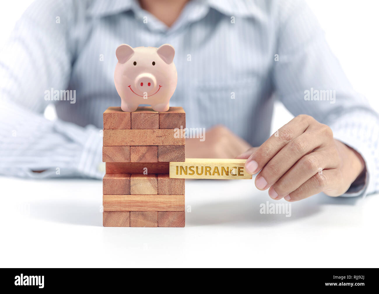 pink ceramic piggy bank with wooden stack toy, insurance risk concept ...