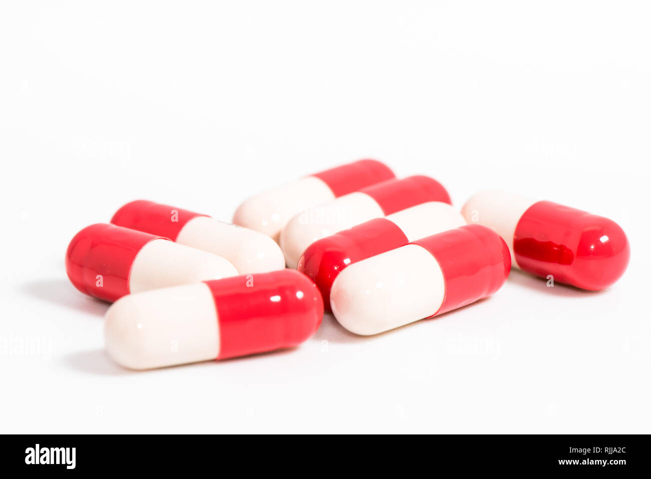 Red and white capsules on white background Stock Photo - Alamy