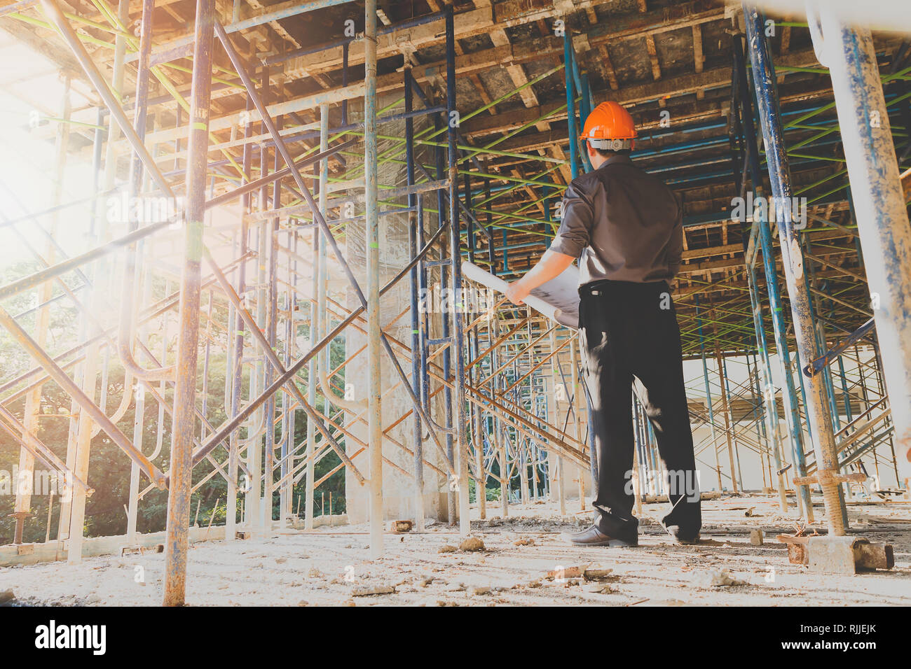 Engineer with blueprint in building construction site Stock Photo - Alamy