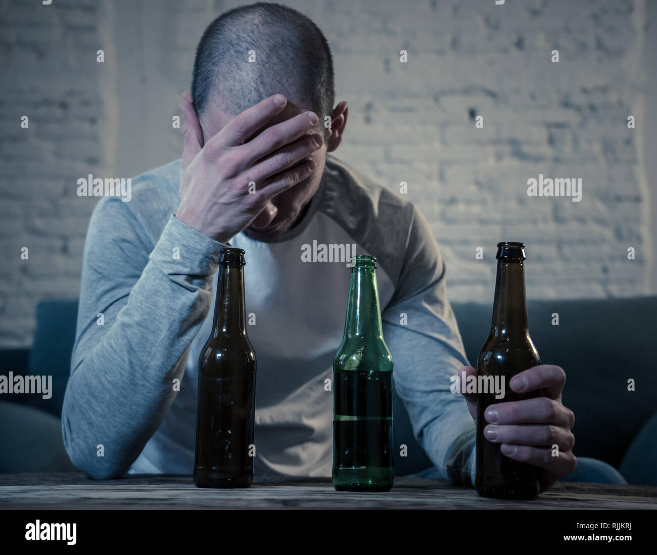 Young sad drunk men drinking beer and alcohol feeling wasted, lonely and desperate in pain and ...