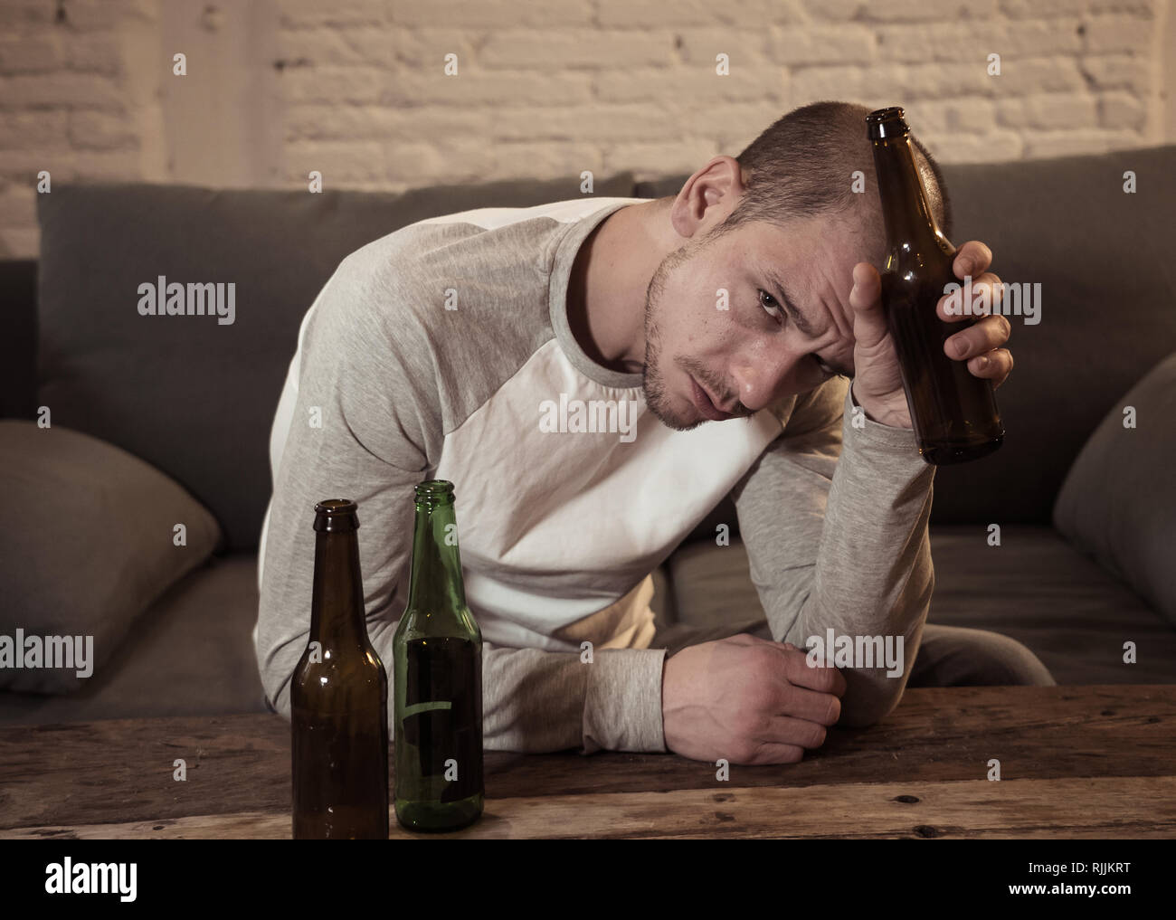 Young sad drunk men drinking beer and alcohol feeling wasted, lonely and desperate in pain and ...