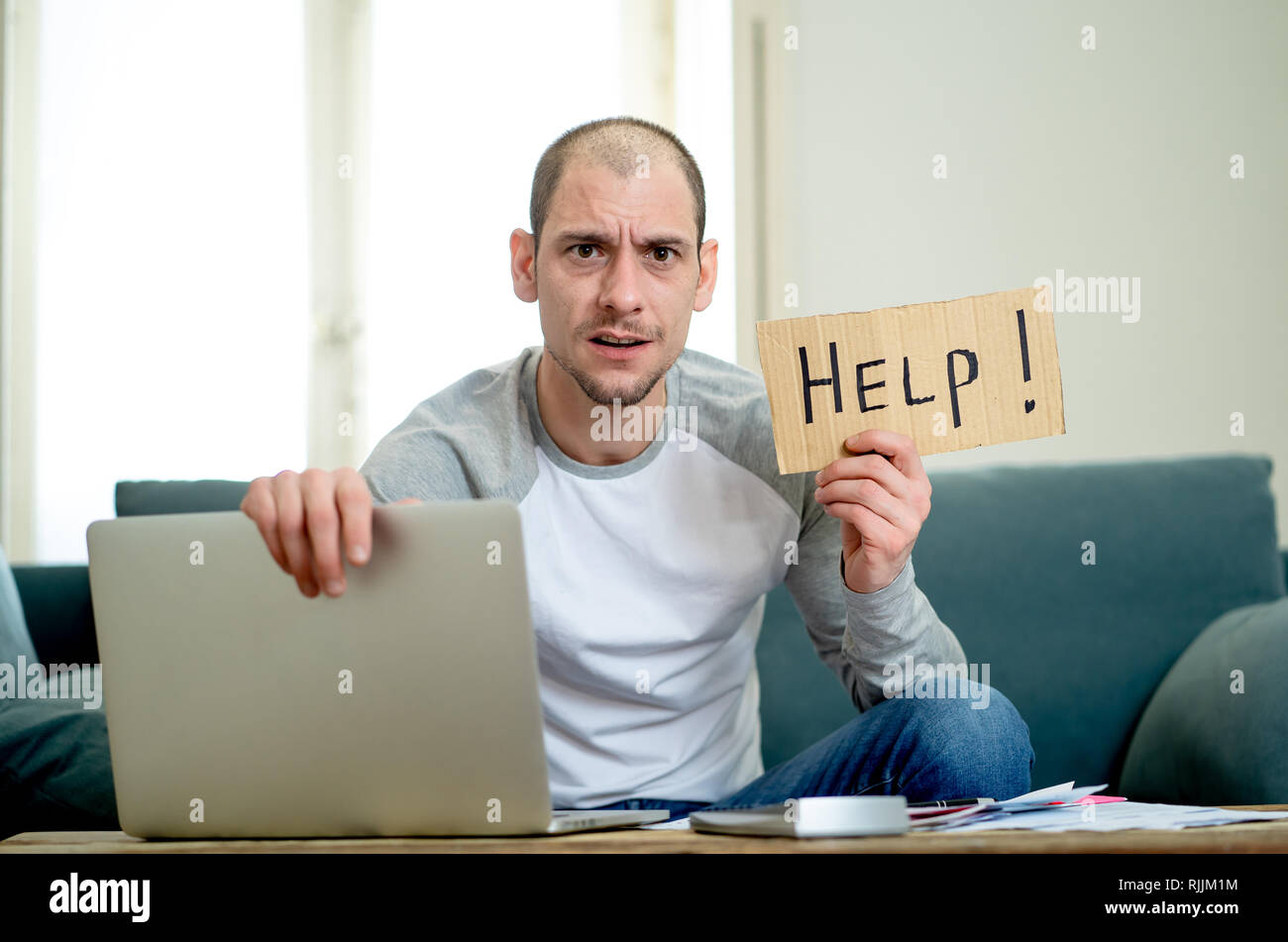 Attractive young man overwhelmed with business and home finances asking ...