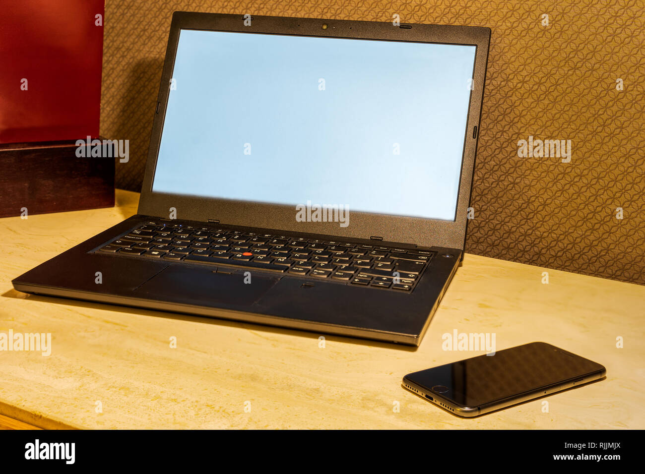 Modern laptop and mobile phone on desk, working on holidays from hotel ...