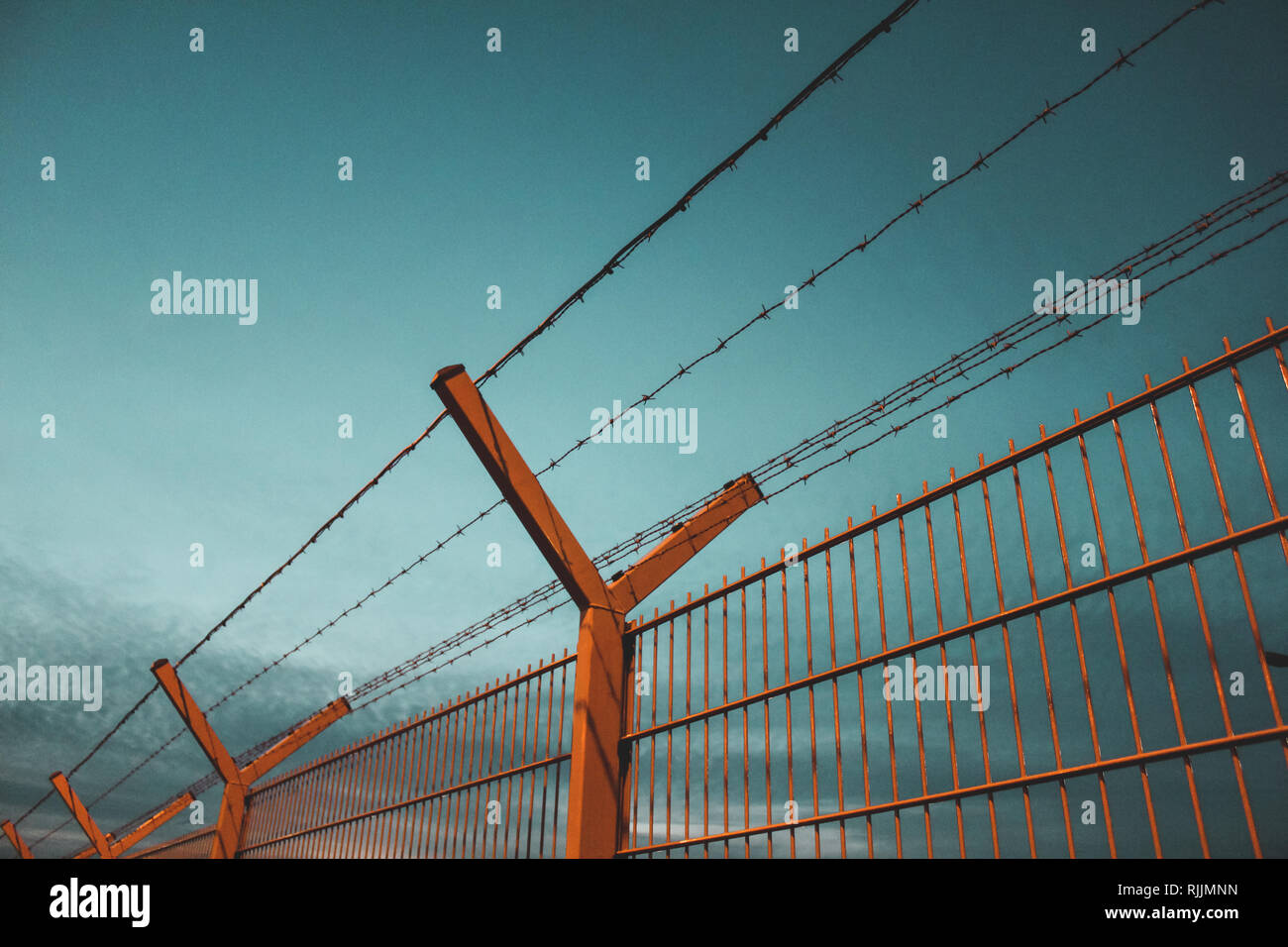 Iron fence with barbed wire during blue hour, protection and border ...