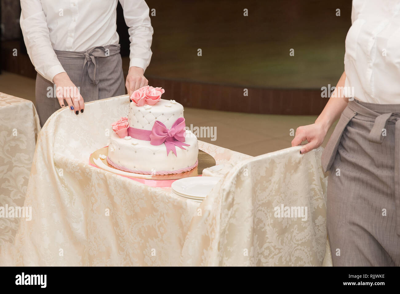 Two waiter carries wedding cake with red rose Stock Photo - Alamy