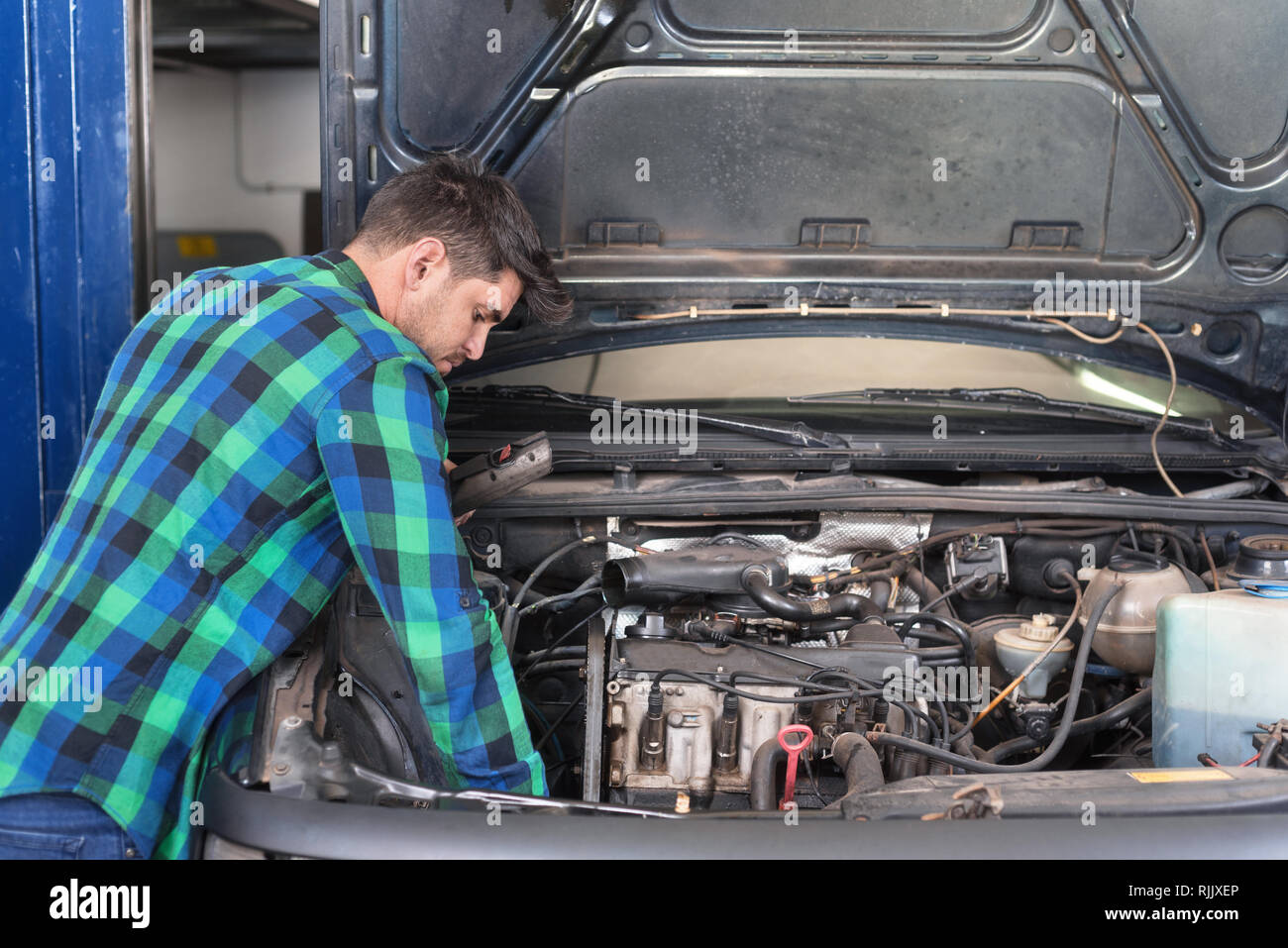 Handsome mechanic talking on the phone while repairing a car Stock ...