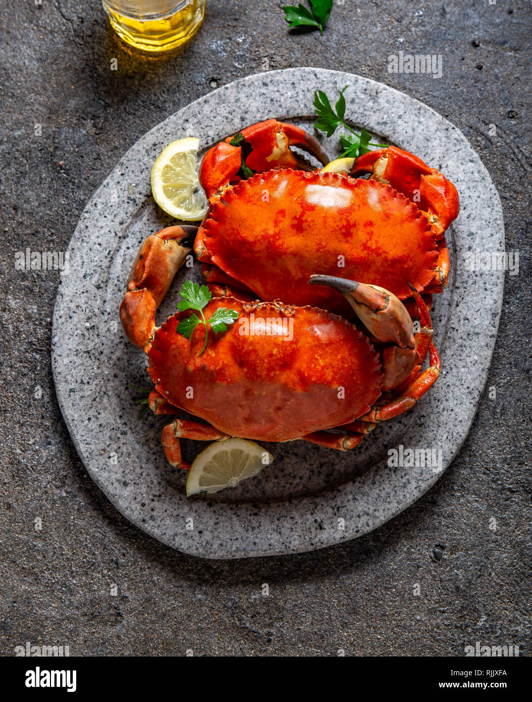 Whole cooked crabs on white plate with lemon and beer. Gray concrete ...