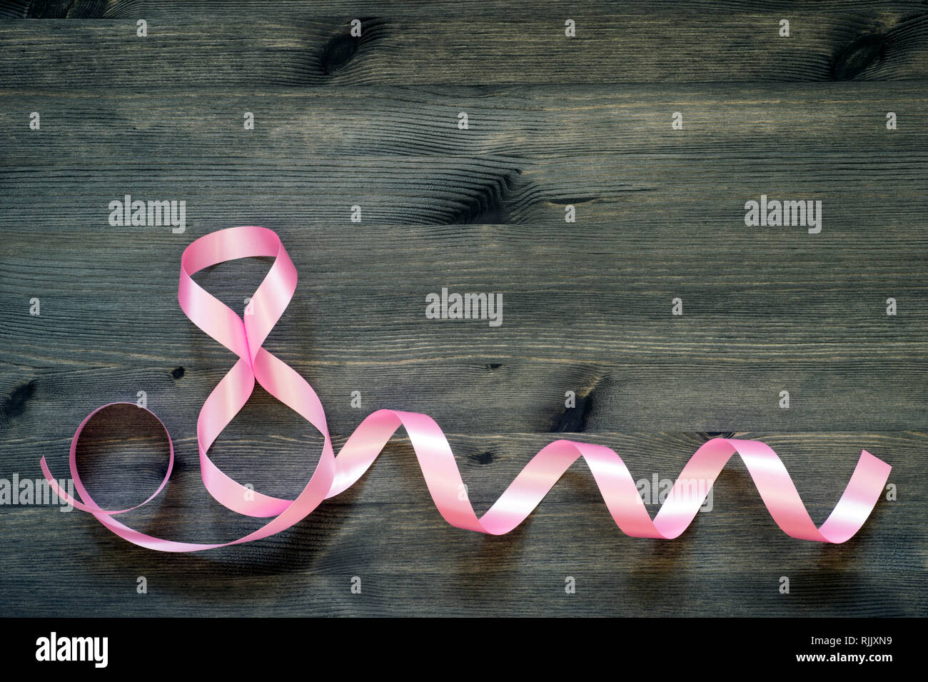 Pink ribbon with number eight on wooden vintage background. The ...
