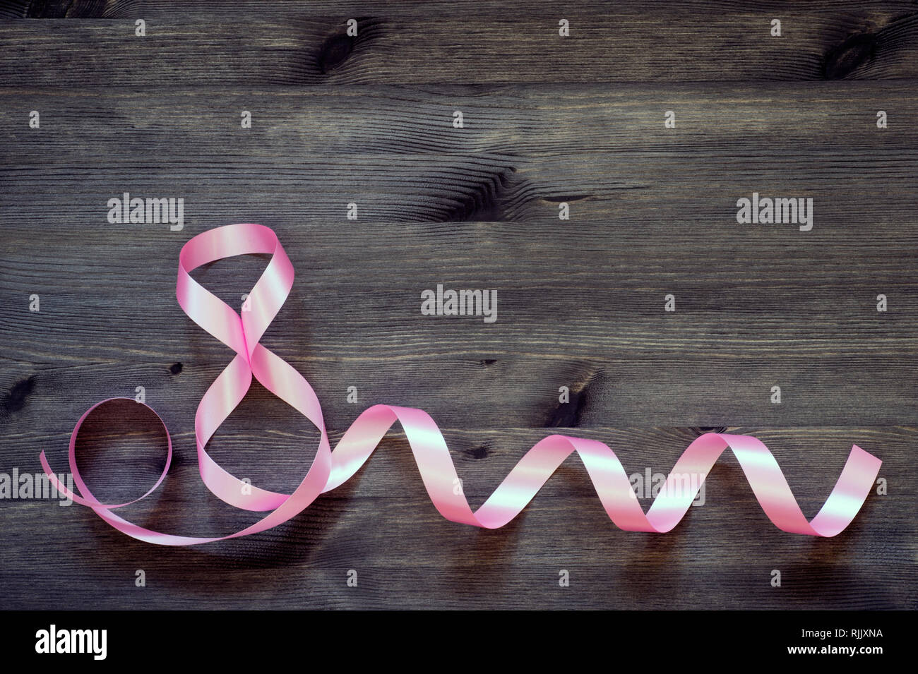 Pink ribbon with number eight on wooden vintage background. The ...