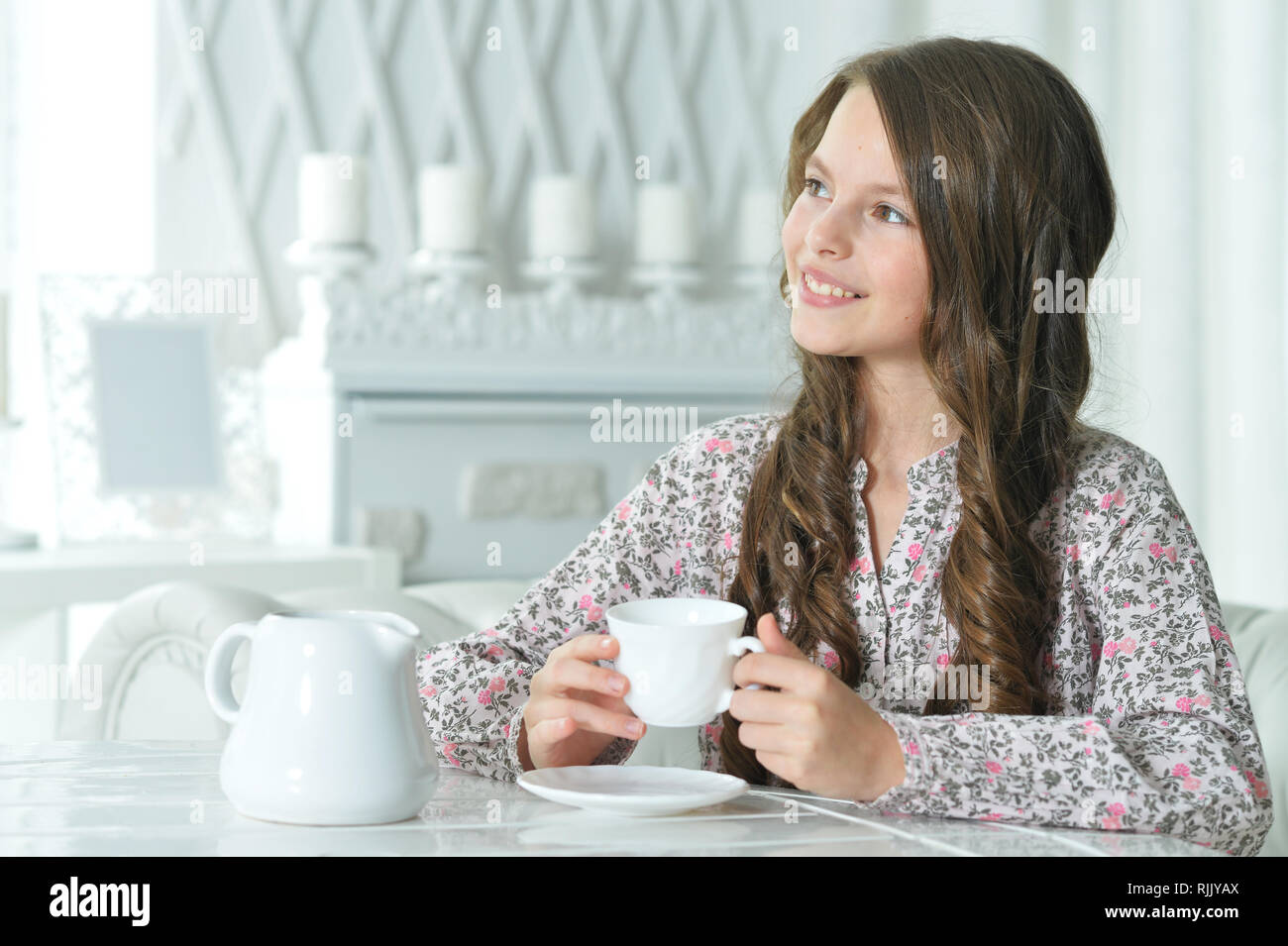 Portrait of cute girl drinking tea at light kitchen Stock Photo - Alamy
