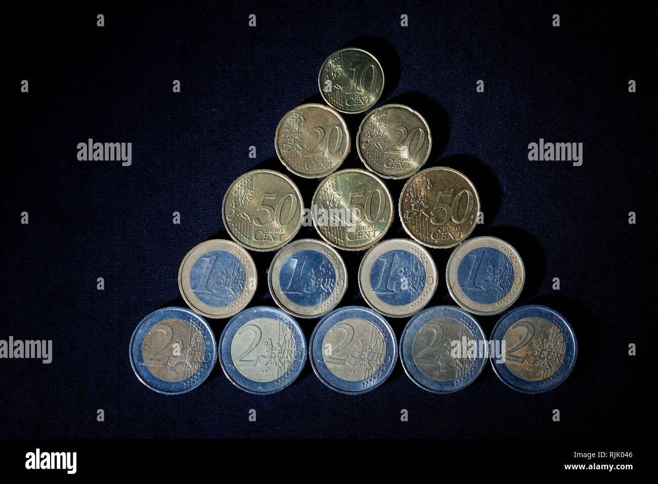A triangle made with euro coins and cents on black background Stock ...