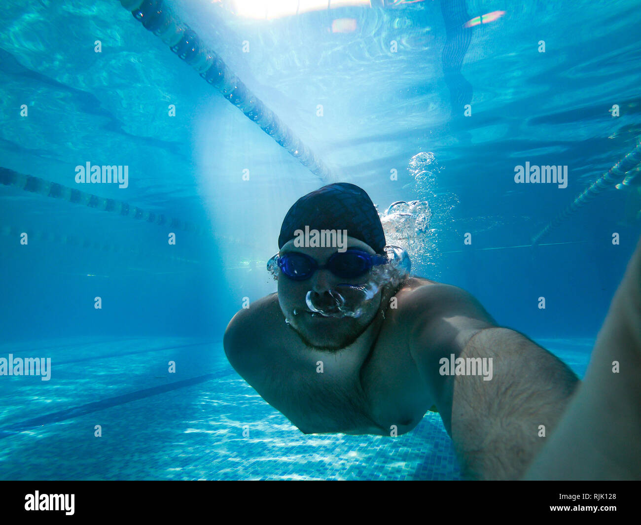 man underwater holding breath in pool. blue goggles Stock Photo - Alamy