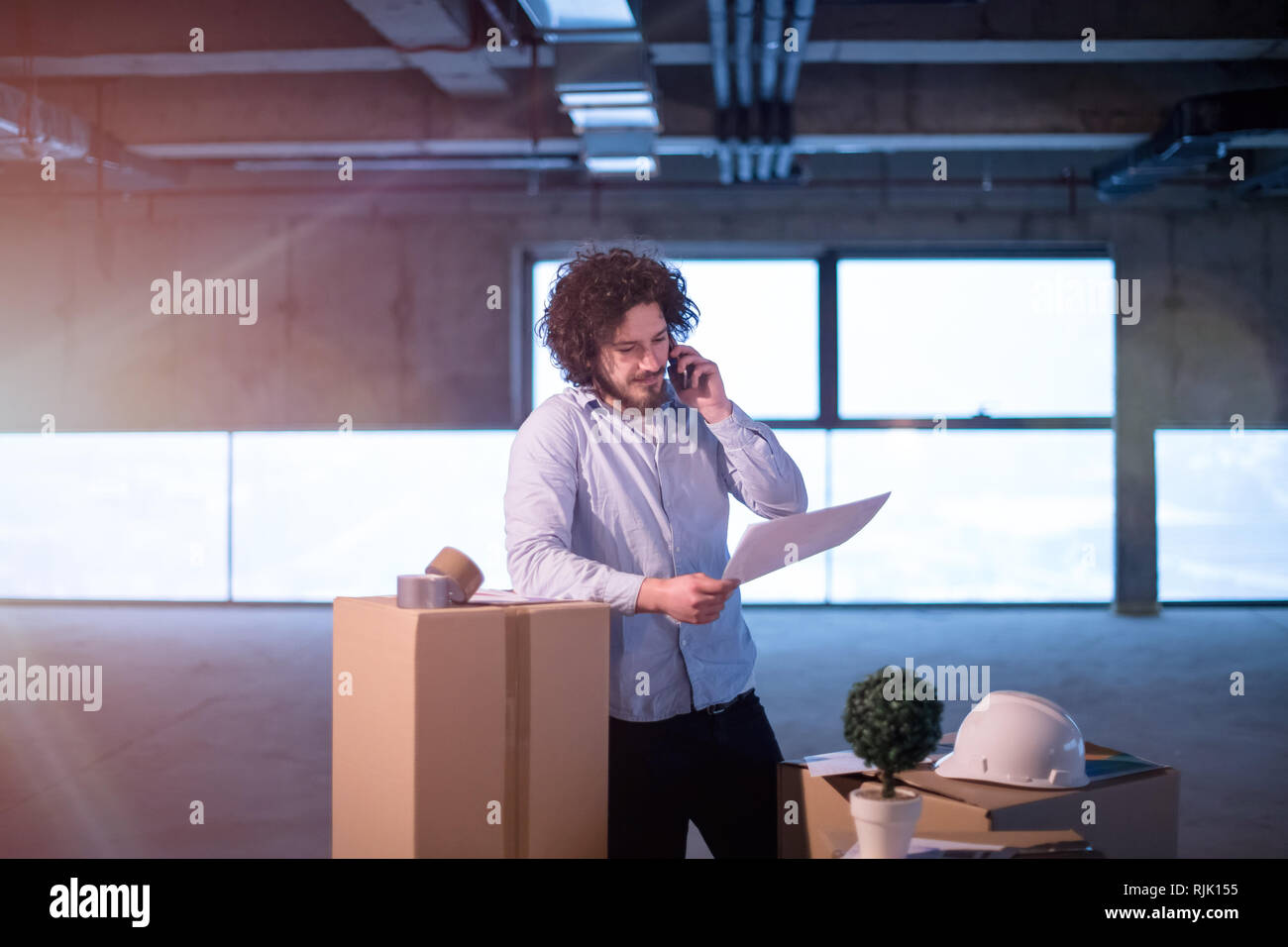 young male architect on construction site checking documents and ...