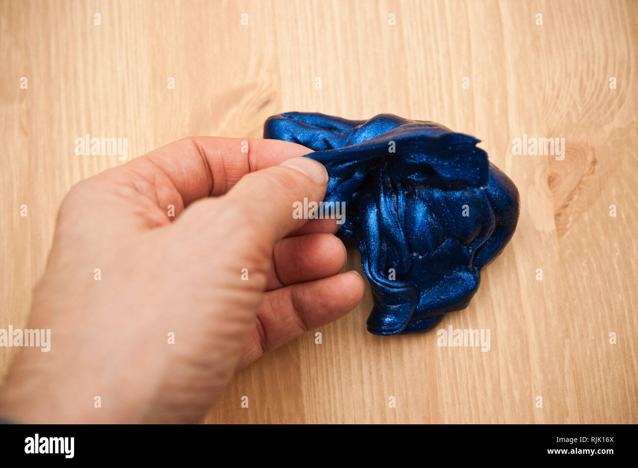 male hand playing with a blue silly putty Stock Photo - Alamy