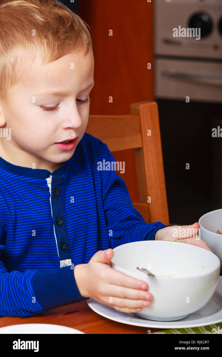 Happy childhood. Blond boy kid child eating corn flakes cereal with ...