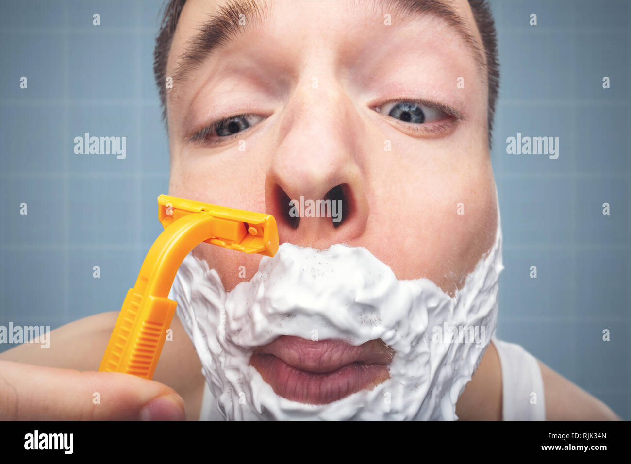 Funny portrait of a man shaving his beard with a razor and foam Stock Photo - Alamy