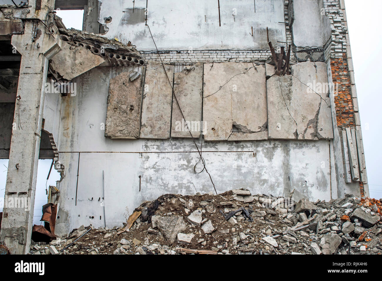 The concrete wall of the destroyed large building with hanging concrete ...