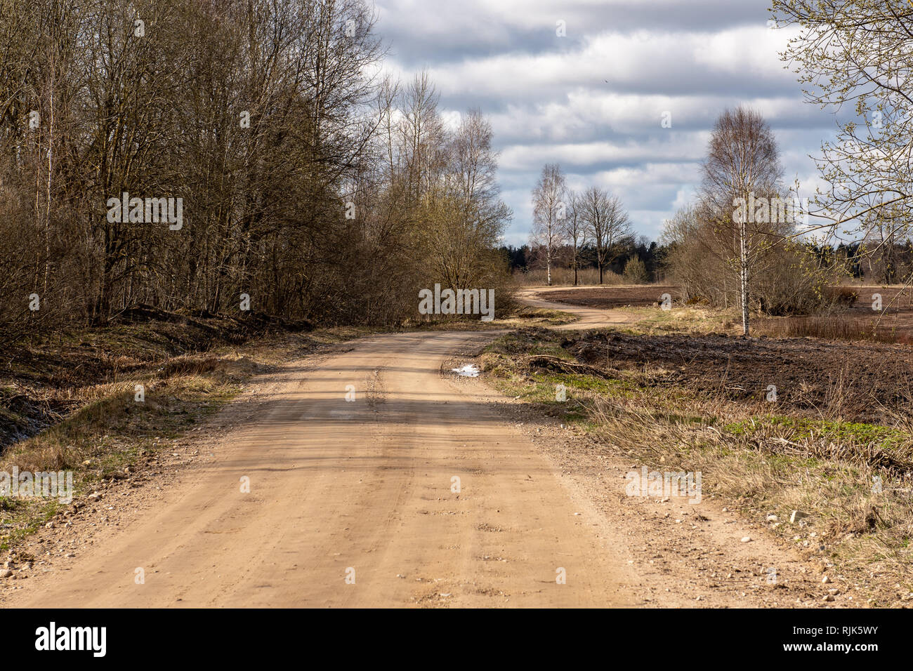empty country gravel road with mud puddles and bumps. dirty road surface with sand and small ...