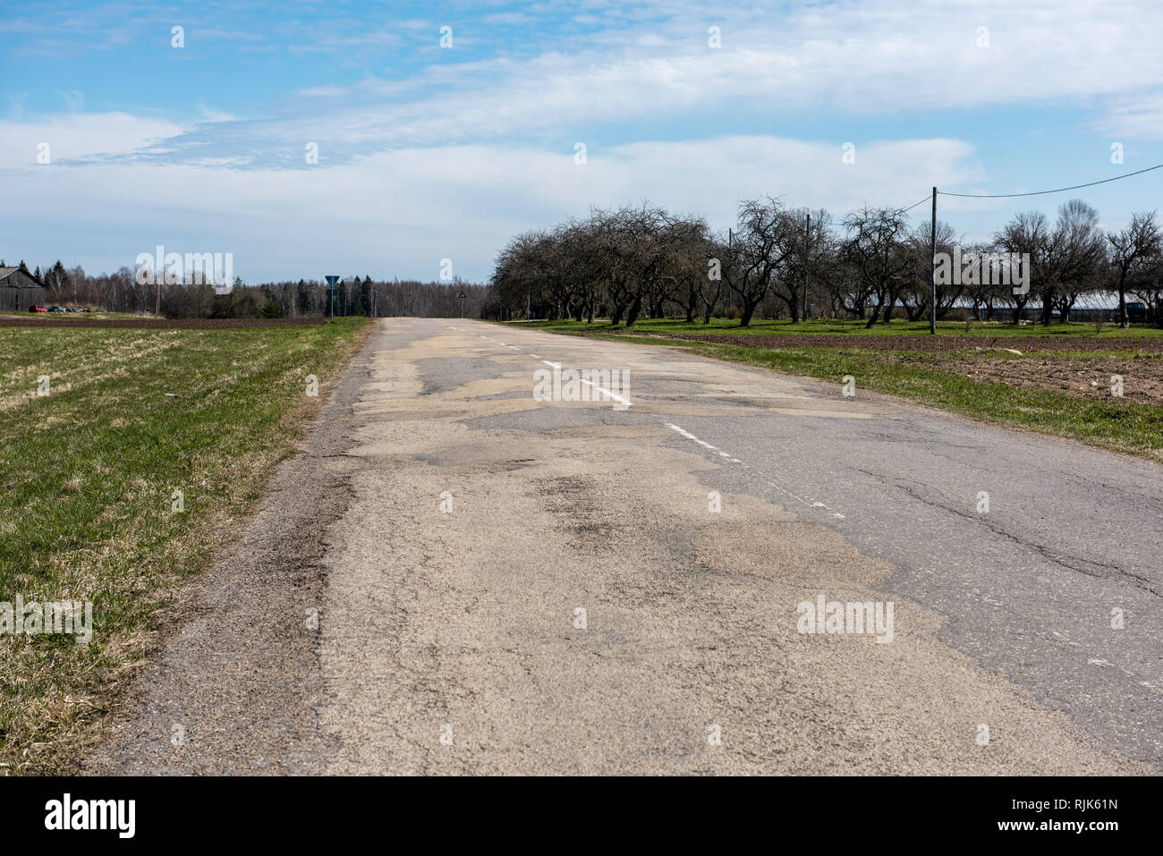 empty country gravel road with mud puddles and bumps. dirty road surface with sand and small ...