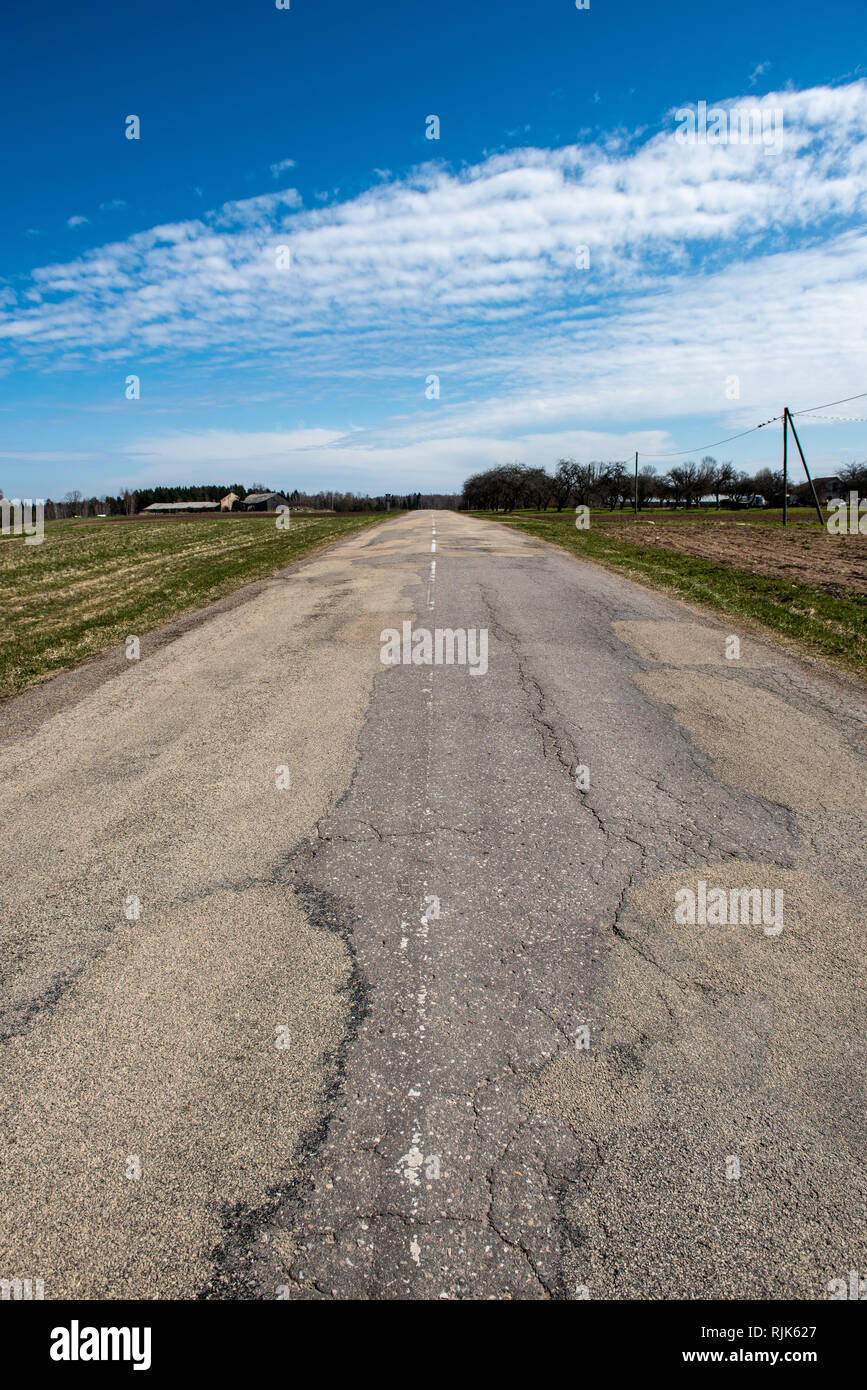 empty country gravel road with mud puddles and bumps. dirty road surface with sand and small ...