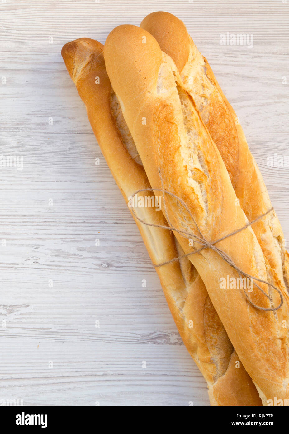 Fresh french baguettes on white wooden surface, top view. Overhead ...