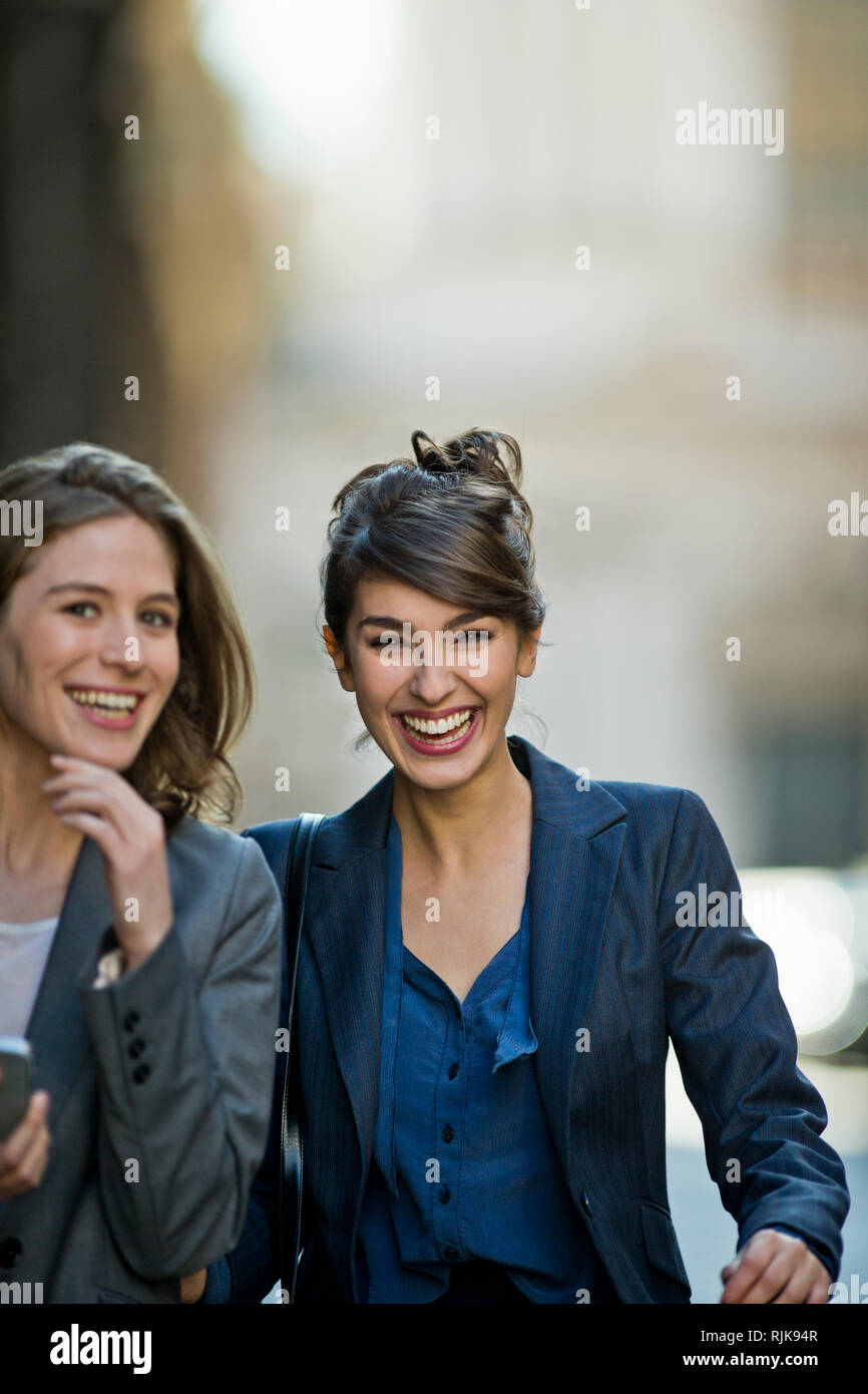 Two laughing young woman chat happily while walking home from the ...