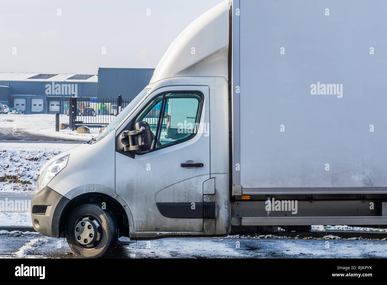 white parked van during winter with a warehouse in the background ...