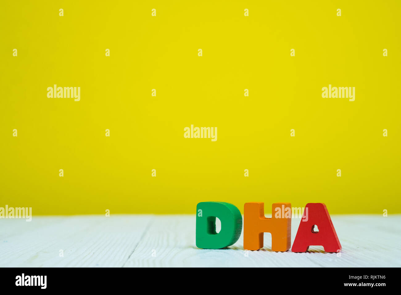 DHA text alphabet on white wooden table. yellow wall background with ...