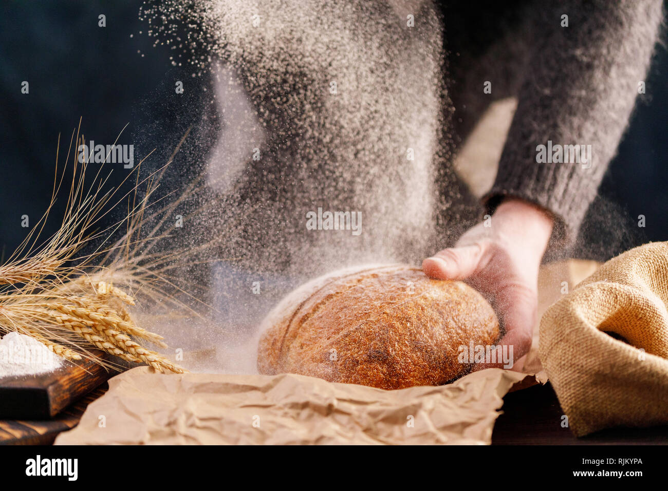 Closeup homemade bread in a man's hand and flour pouring. The concept ...