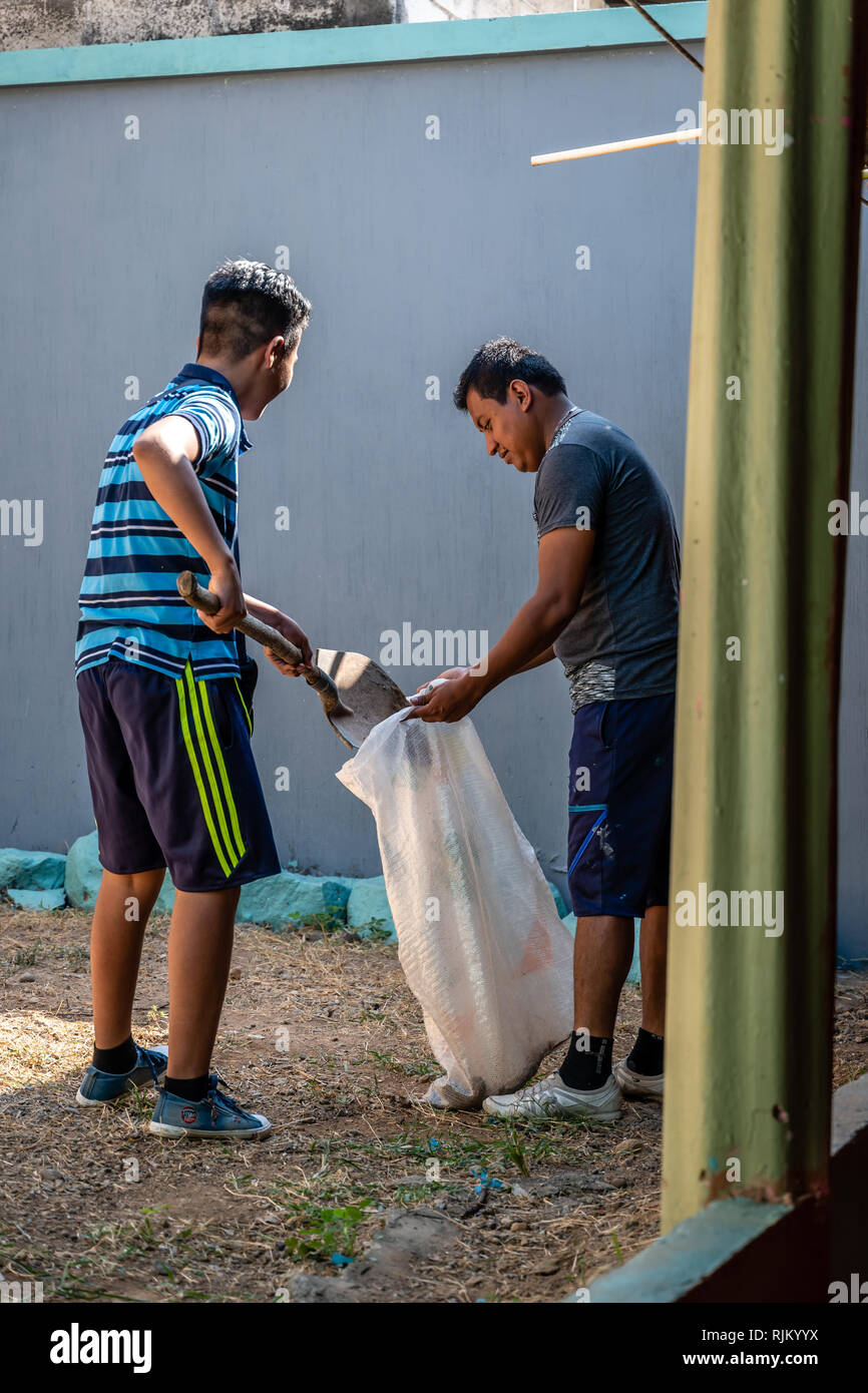 latin man and boy shoveling dirt in Guatemala Stock Photo - Alamy