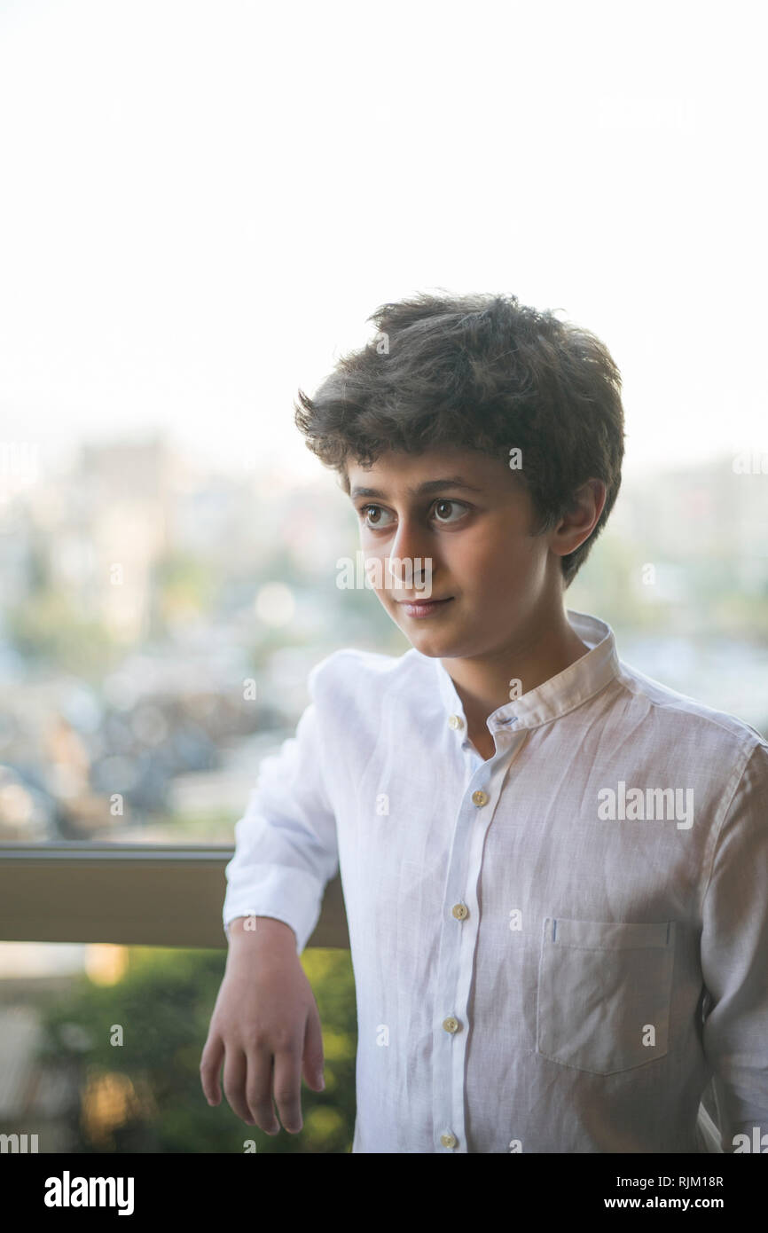 Happy boy leaning against the window looking away smiling Stock Photo ...