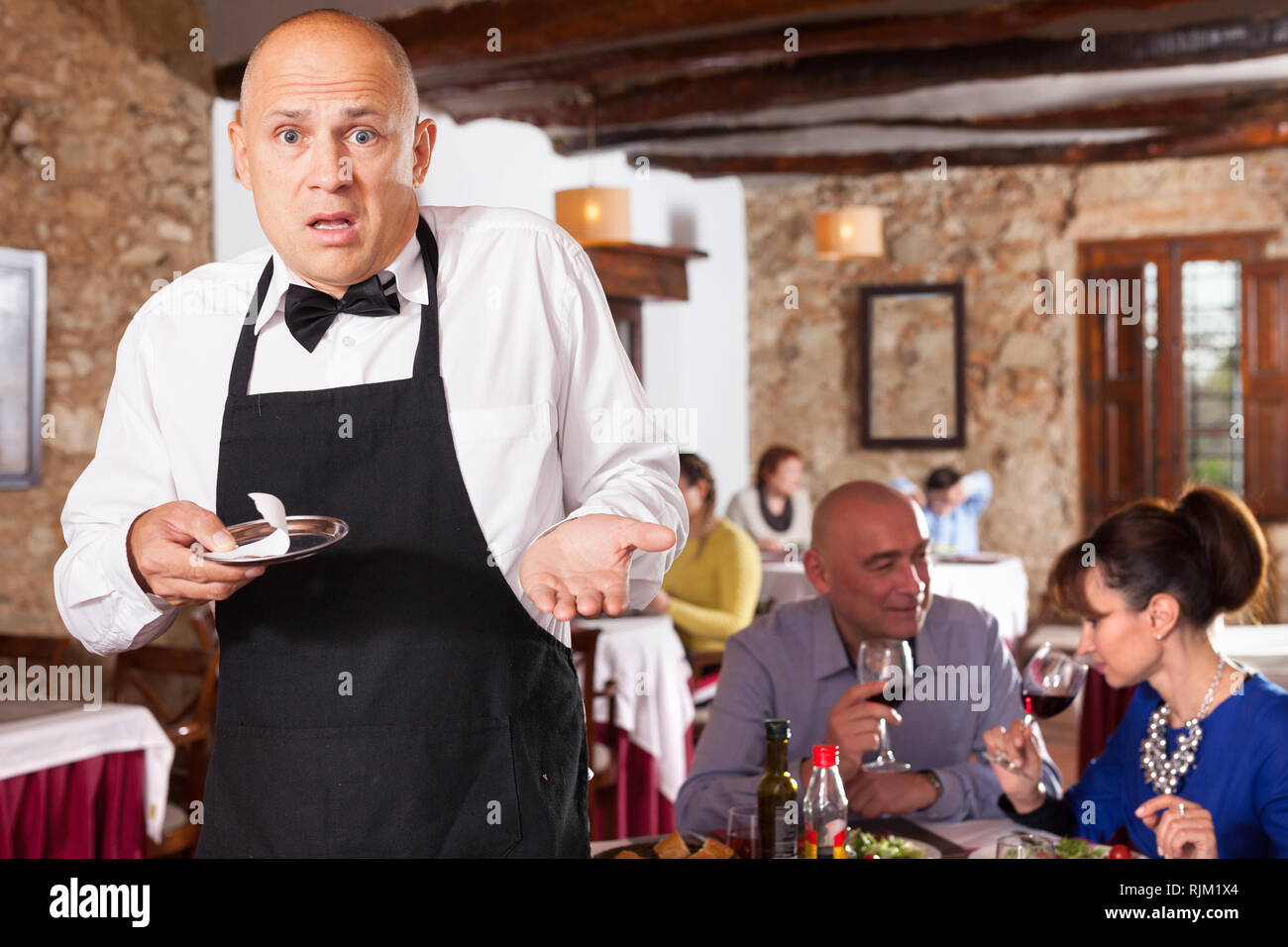 Male waiter expressing his displeasure with small tips from couple of ...
