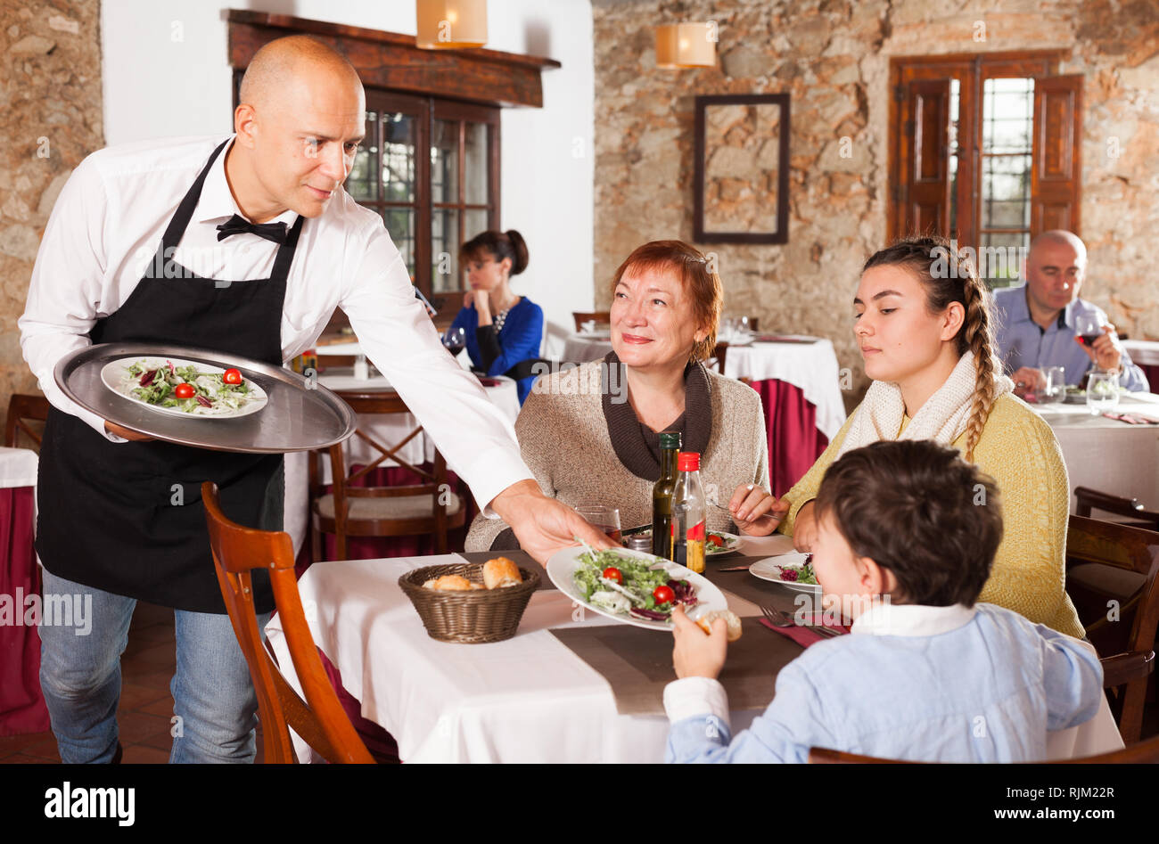 Portrait of two happy women with little boy having dinner in restaurant ...