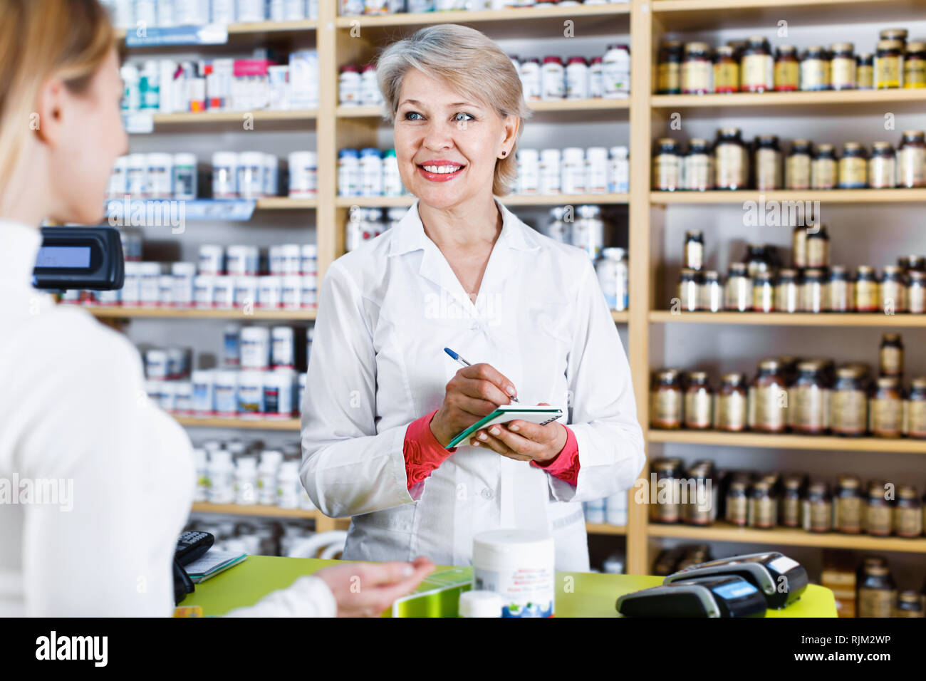 Cheerful mature female seller suggesting useful skin care products in ...