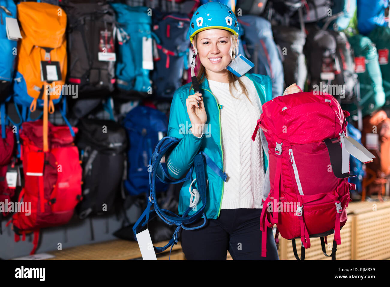 Smiling girl chooses a backpack for camping from assortment in the ...