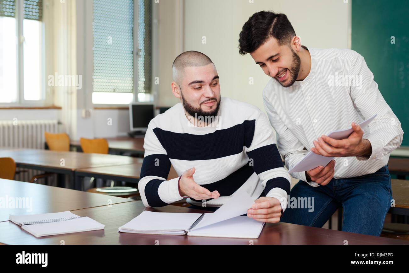 Two young handsome students having discussion about their university ...