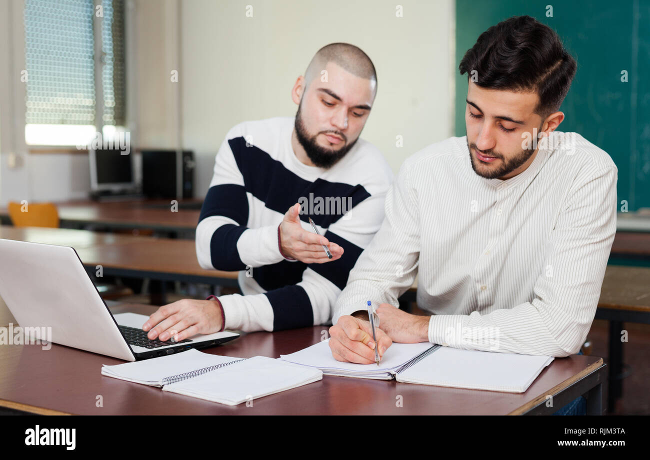 Two male university students sitting at desk preparing for exams ...