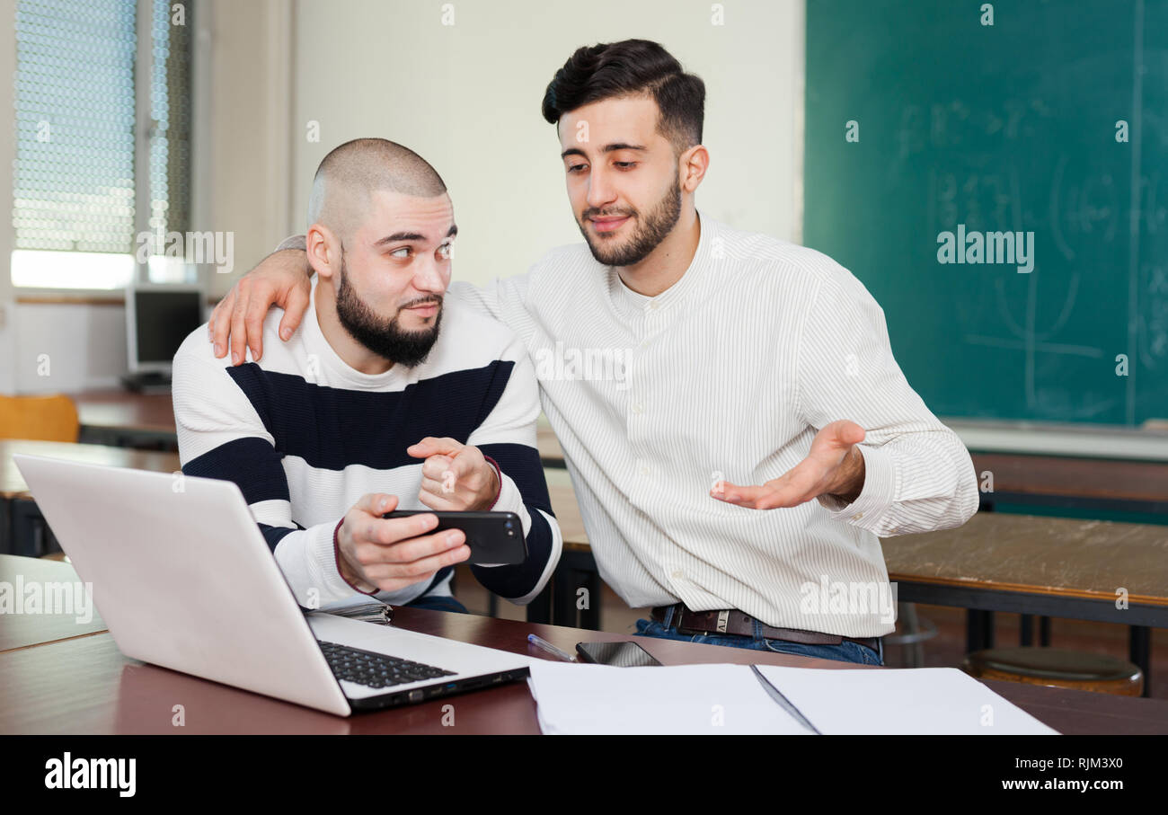 Male university students using their mobile phone instead of studying ...