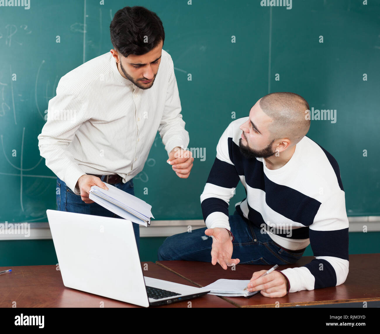 Portrait of two young guys working on their student project near ...