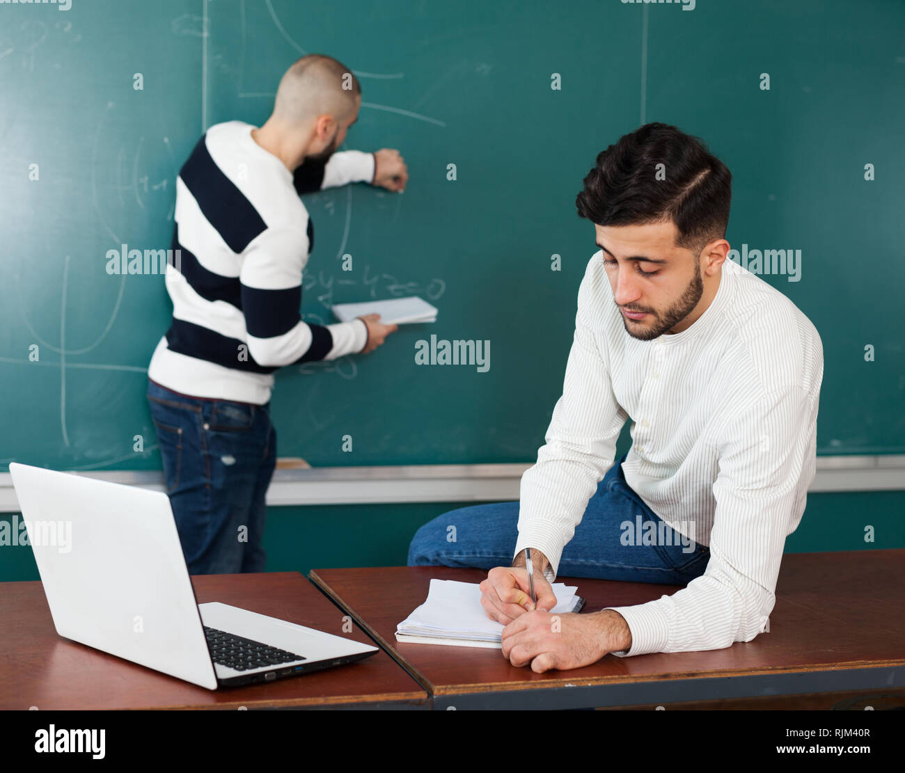 Portrait of two young guys working on their student project near ...