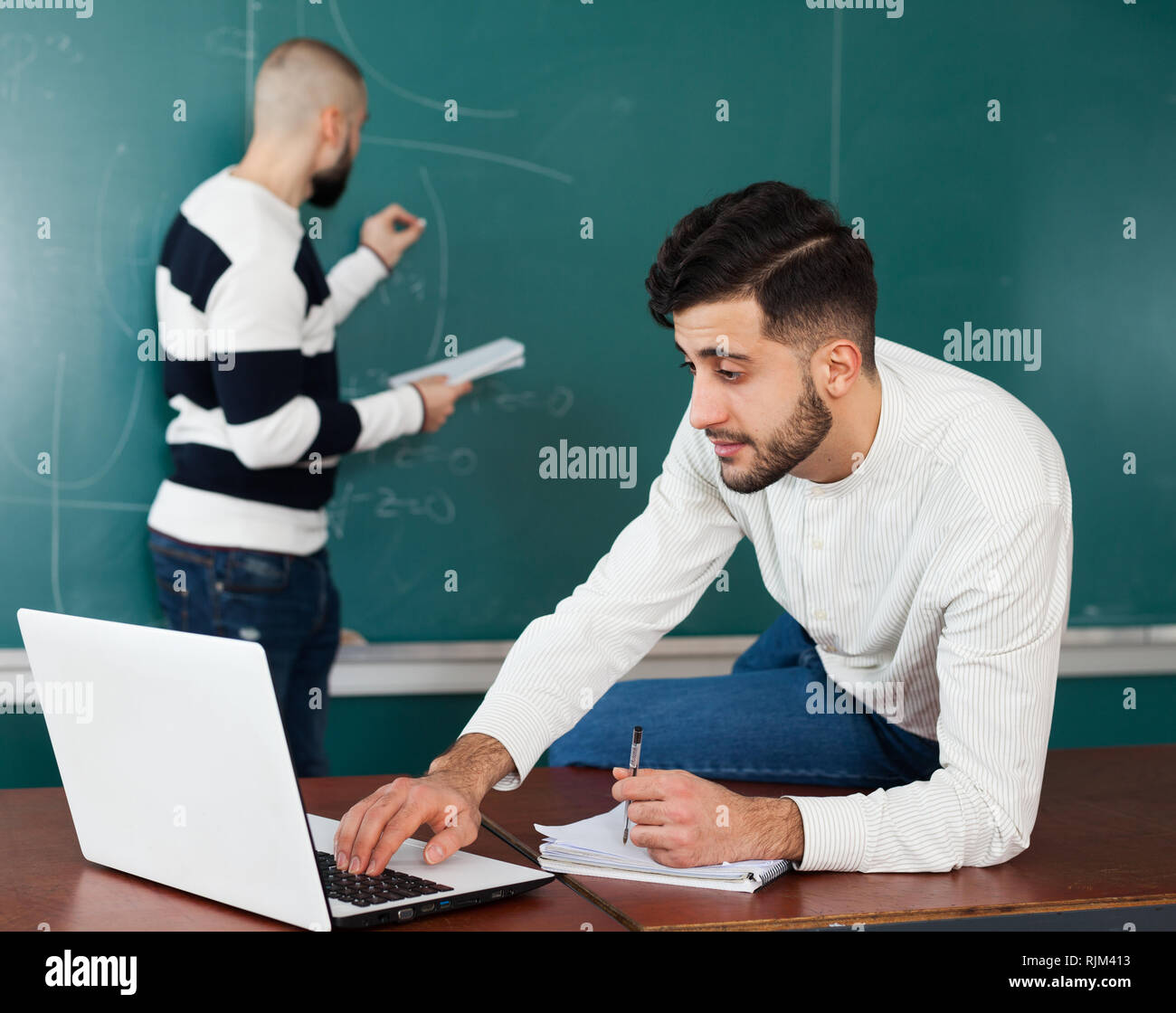 Portrait of two young guys working on their student project near ...