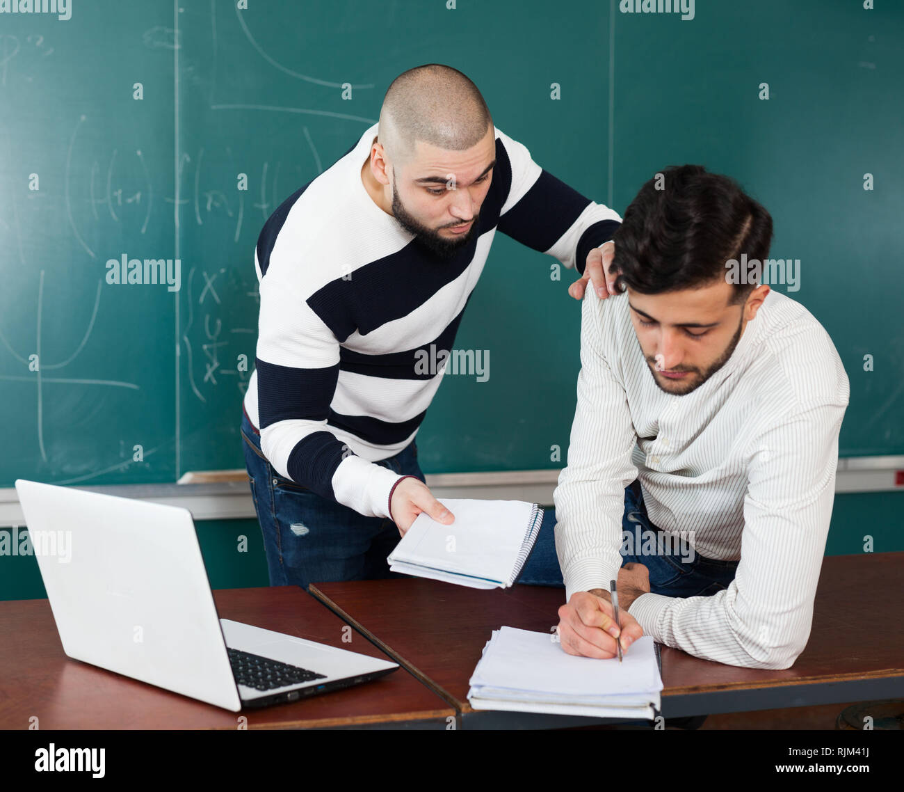 Two male university students preparing for exams together at classroom ...