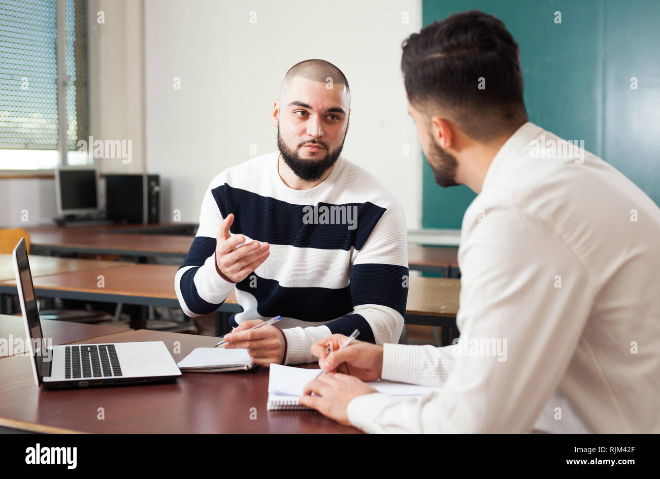 Two male university students sitting at desk preparing for exams ...